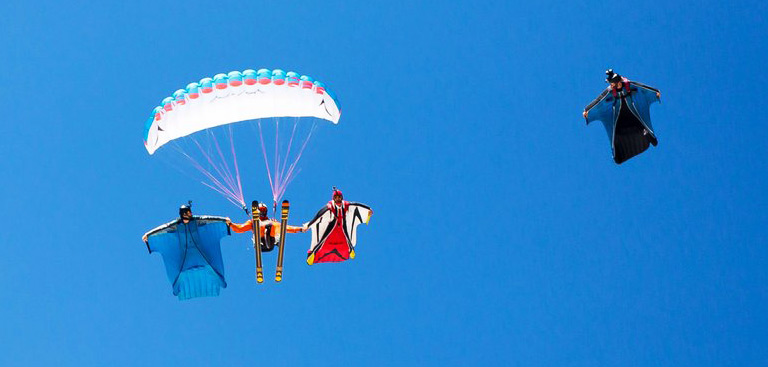 4 pros du wingsuit s'accrochent à un speedrider en plein ciel